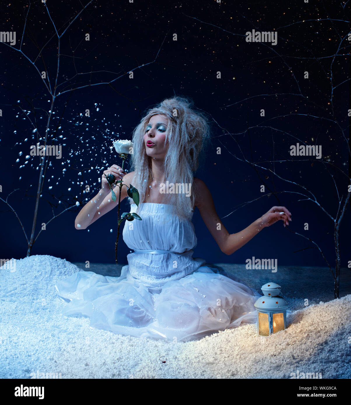 portrait of beautiful winter fairy nymph girl sitting on snow and ...