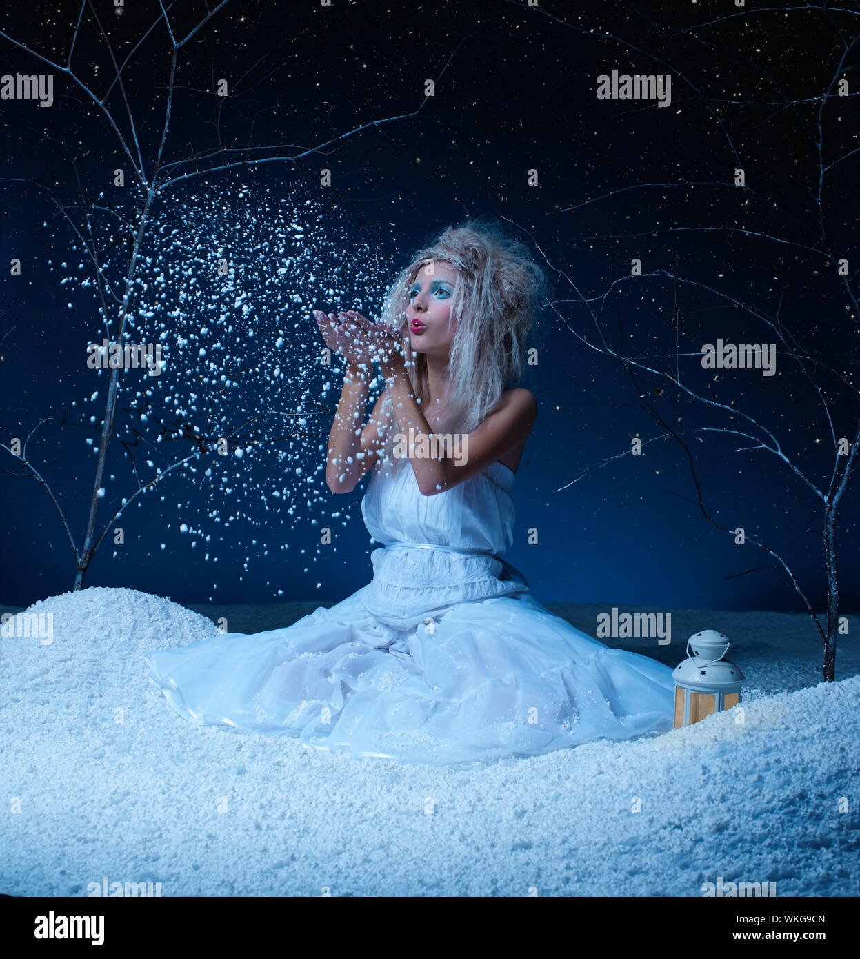 portrait of beautiful frozen fairy nymph girl sitting on snow and ...