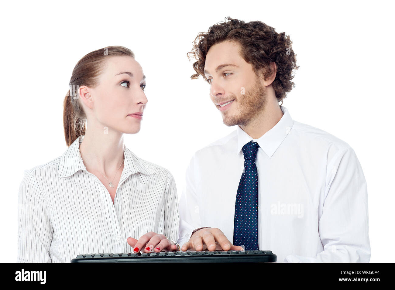 Two executives typing on keyboard, looking each others Stock Photo - Alamy