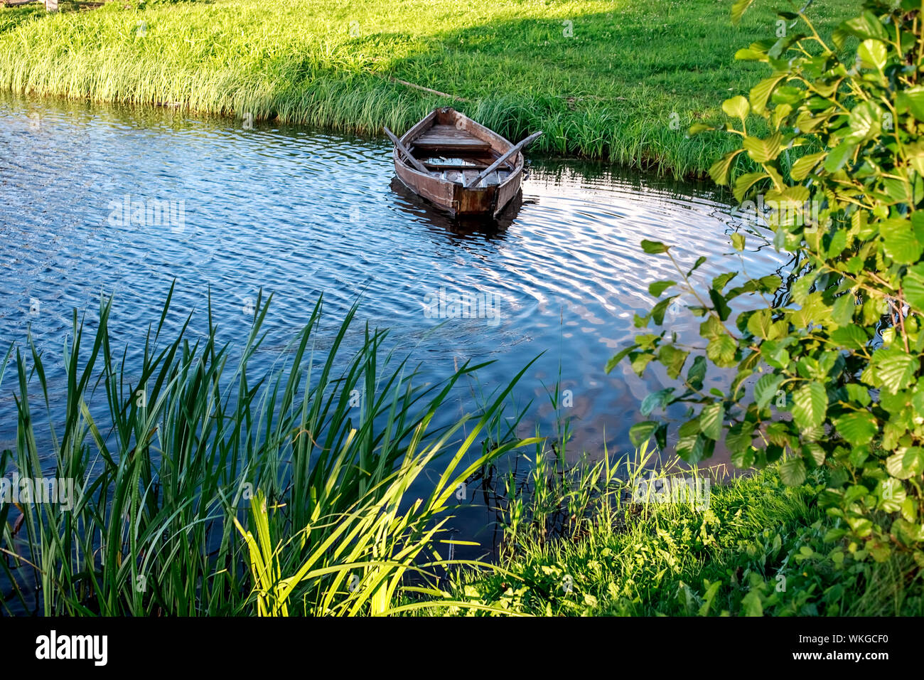 A small wooden rowing boat with a broken bottom on a calm lake near the ...