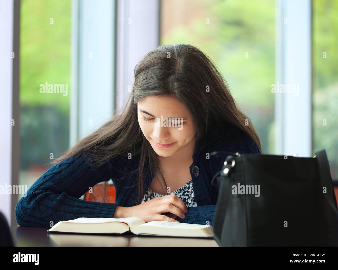 College student studying at school, reading book Stock Photo - Alamy
