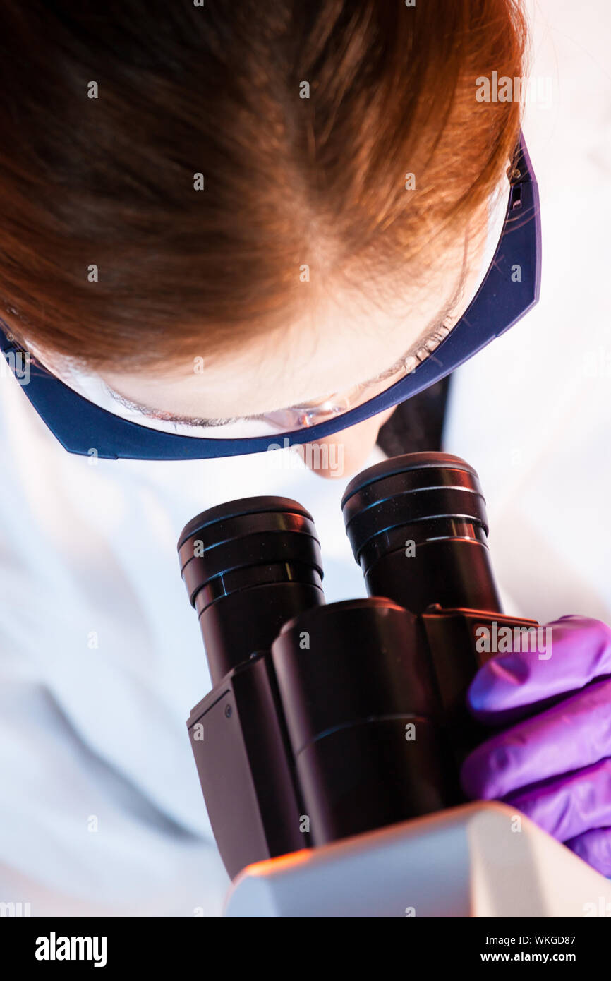 Woman looking into microscope eyepiece hi-res stock photography and ...