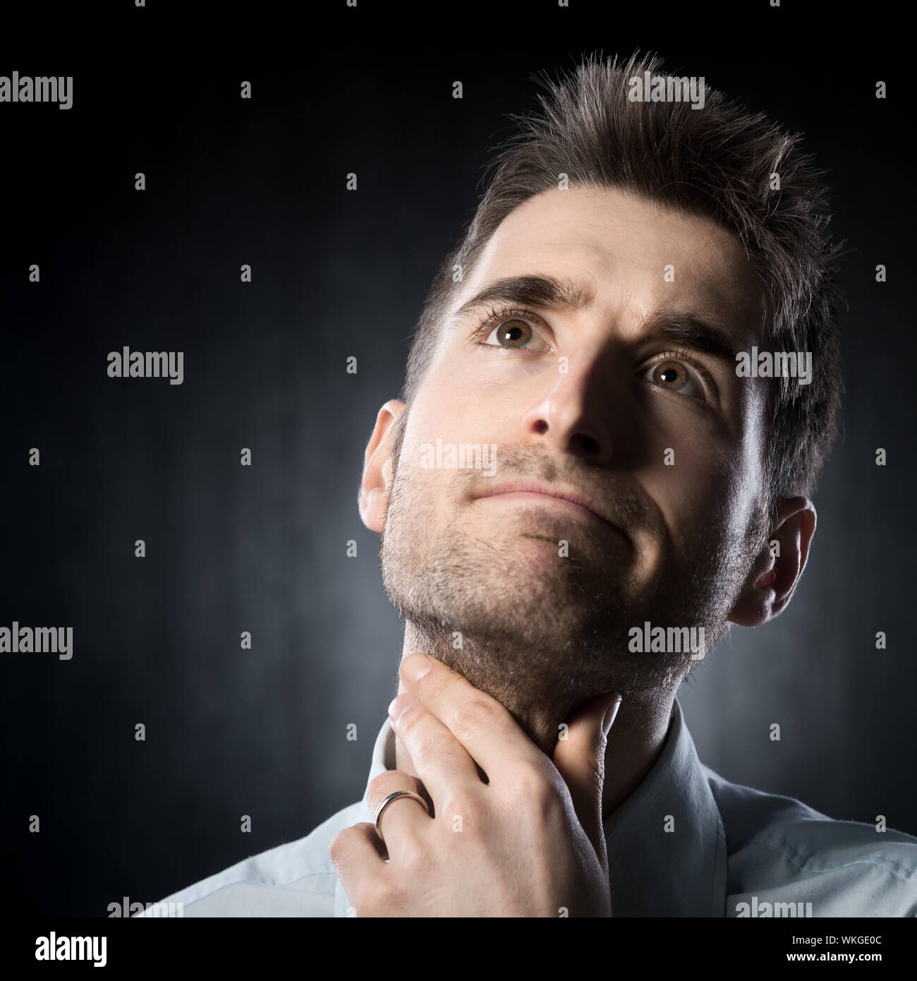 Young man touching his neck with displeased expression Stock Photo - Alamy