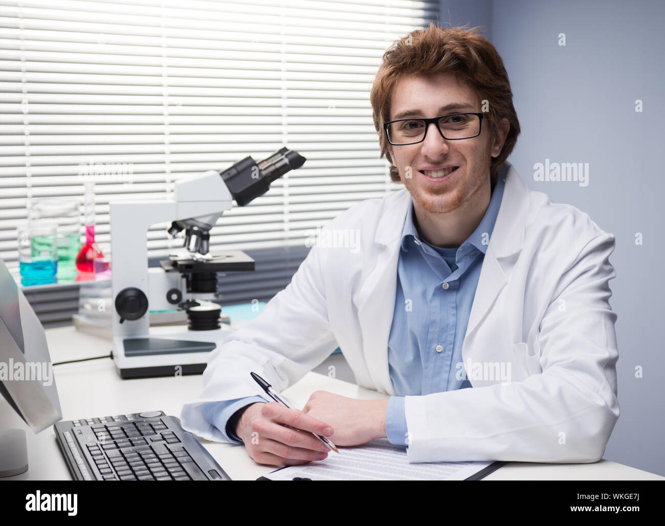 Young researcher writing notes at desk in the chemical lab Stock Photo ...