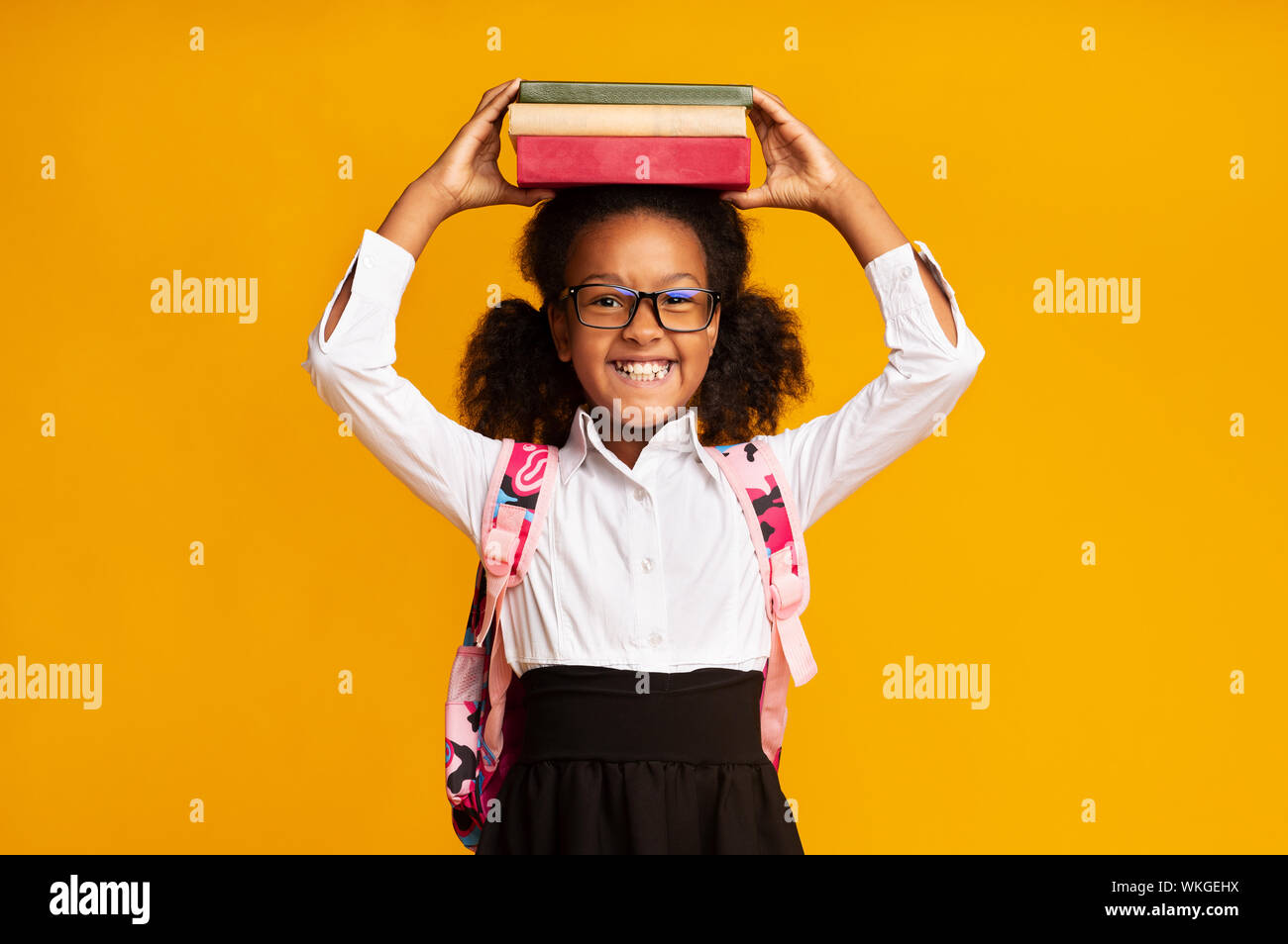 Smiling Black Schoolgirl Holding Books On Head, Yellow Background Stock ...