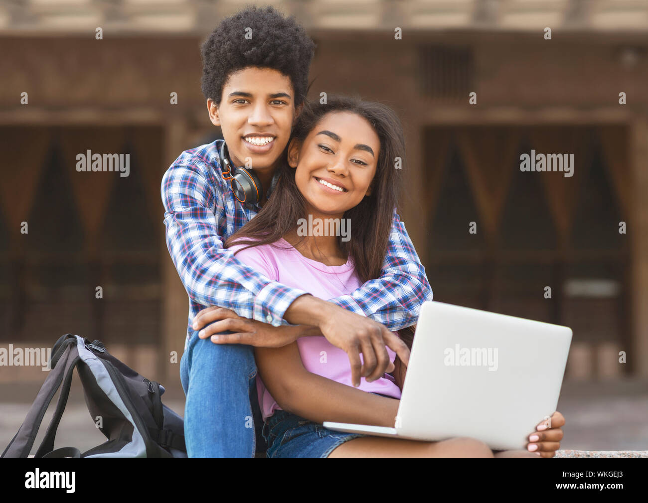 Teenage couple browsing on laptop outdoors posing to camera Stock Photo ...
