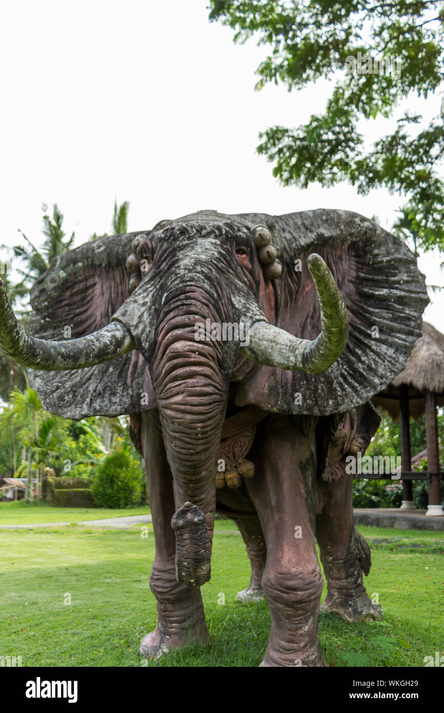 Realistic naturalistic elephant statue standing on a lawn at a park or ...