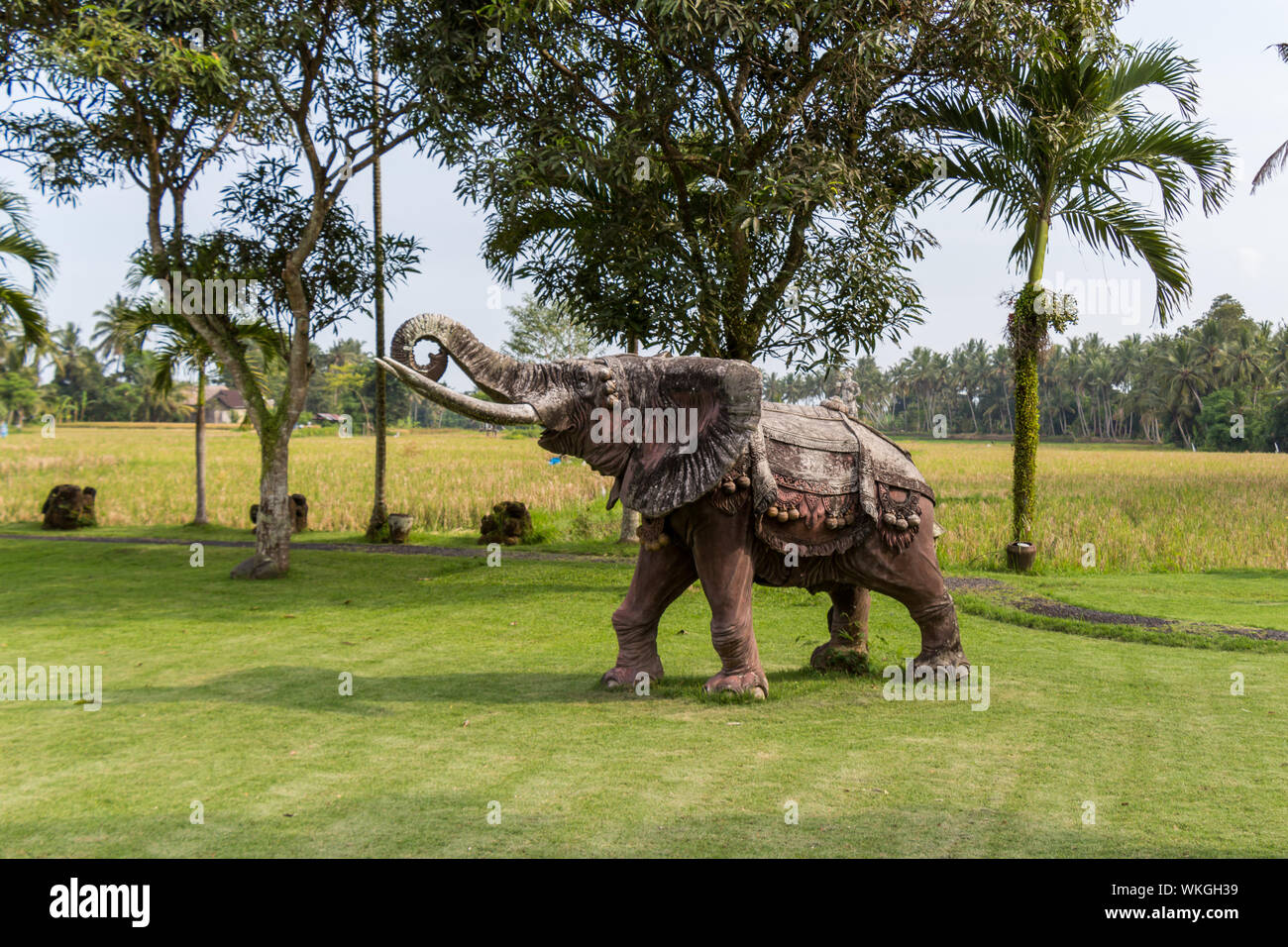 Realistic naturalistic elephant statue standing on a lawn at a park or ...