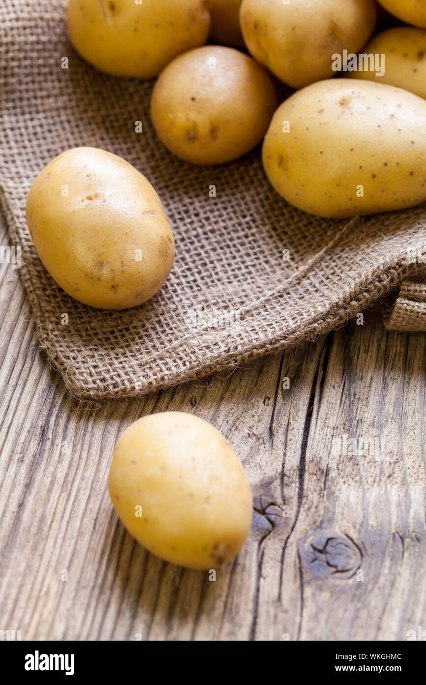 Farm fresh baby potatoes displayed on a hessian sack on a rustic wooden ...