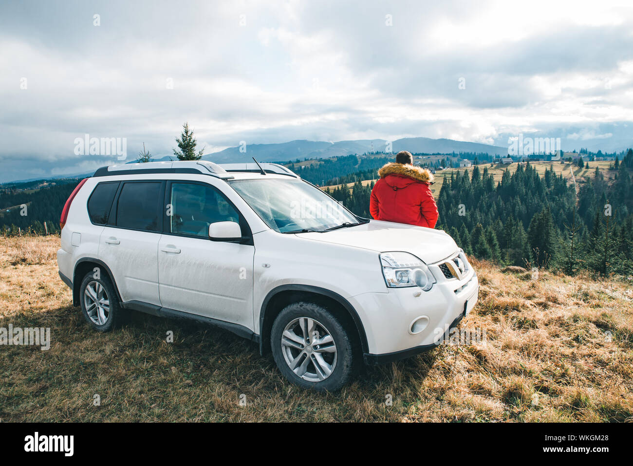 man lean on the car looking at beautiful view of mountains. off road ...
