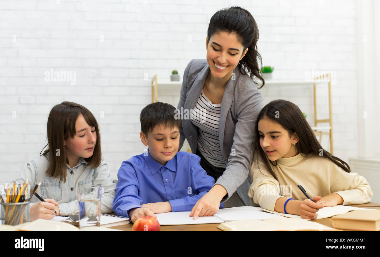 Teacher helping children in classroom, doing homework together Stock ...