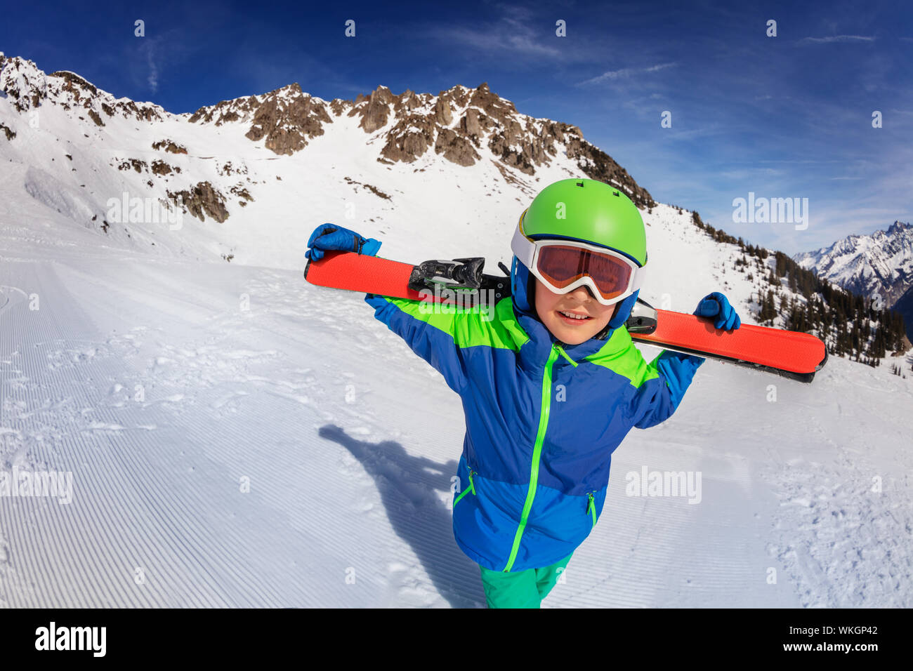 Happy boy carry ski on shoulders walk over slope Stock Photo - Alamy