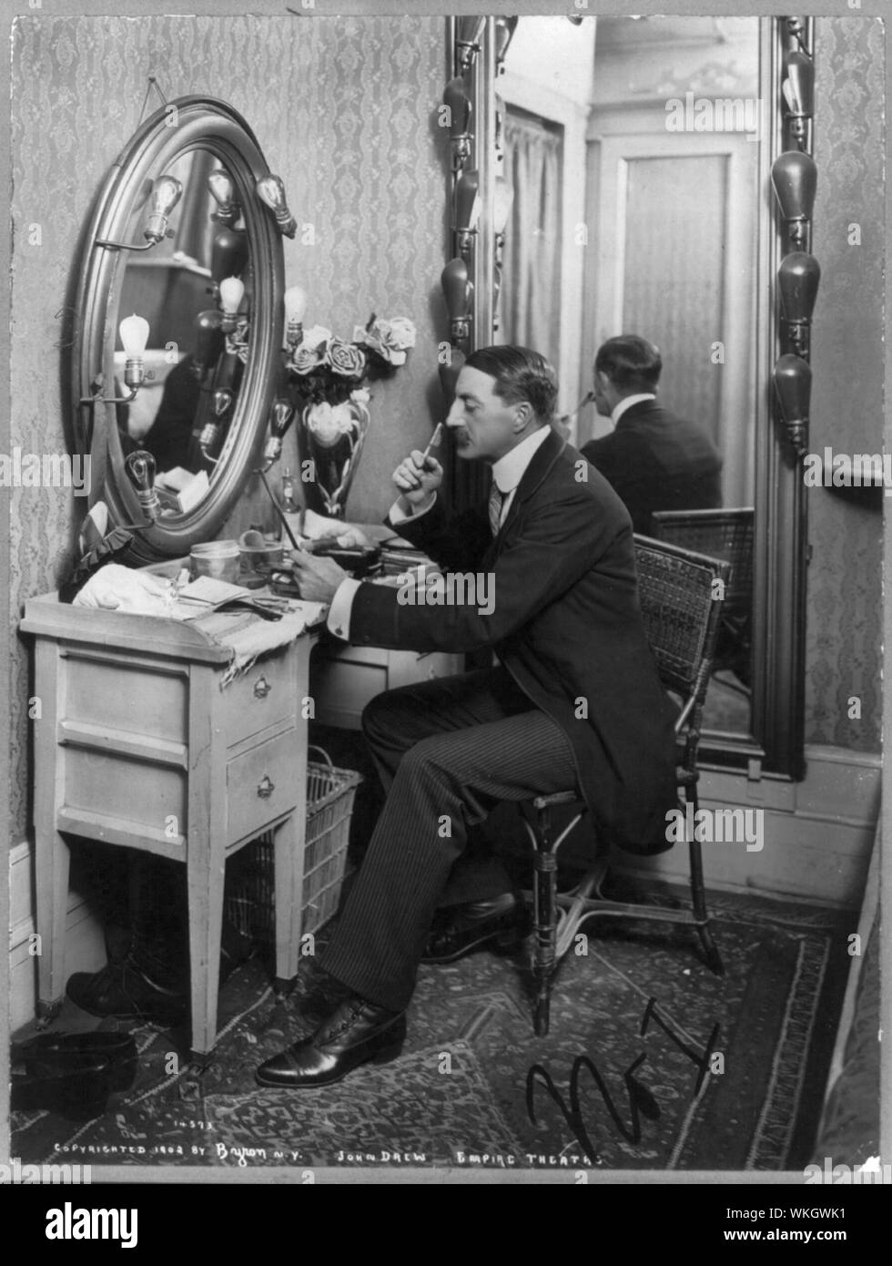 John Drew, 1853-1927, full length, seated at dressing table, facing ...