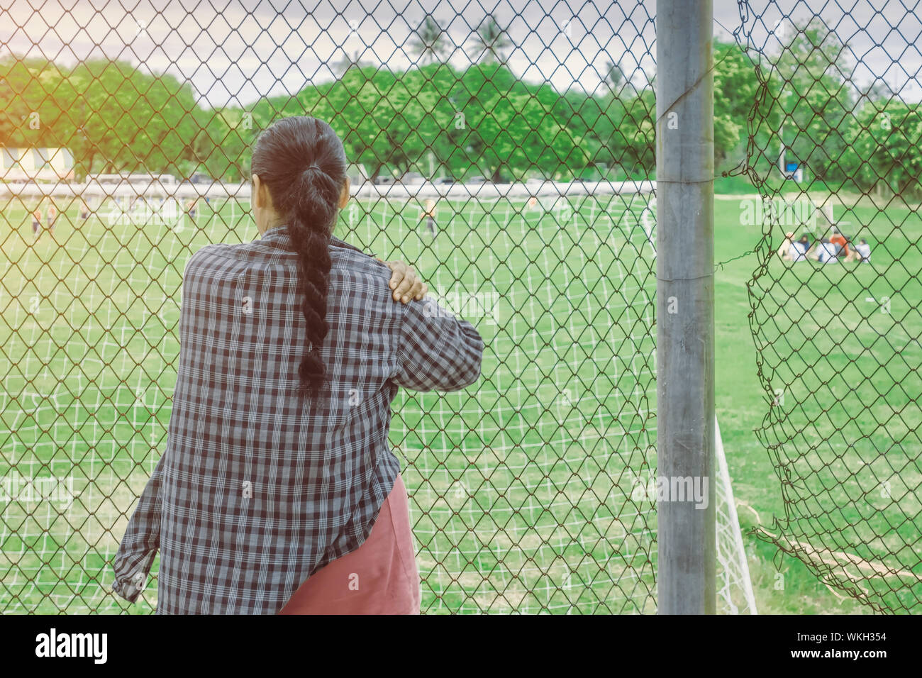 Back view of female parent cheering children playing football in school ...