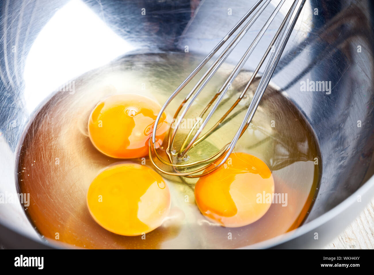 whisking eggs in metal bowl closeup Stock Photo - Alamy