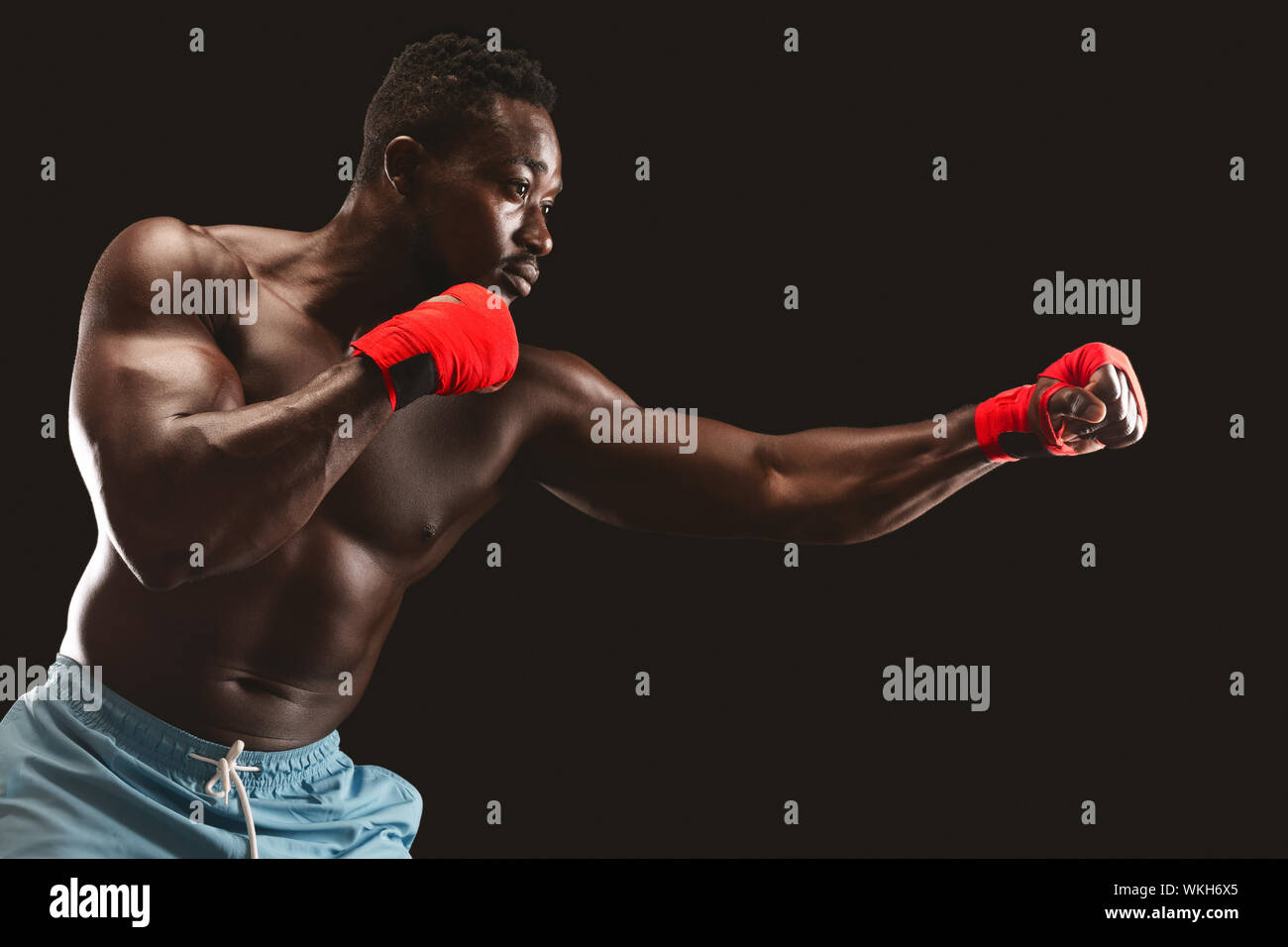 Side view of black fighter making punch over black background Stock ...