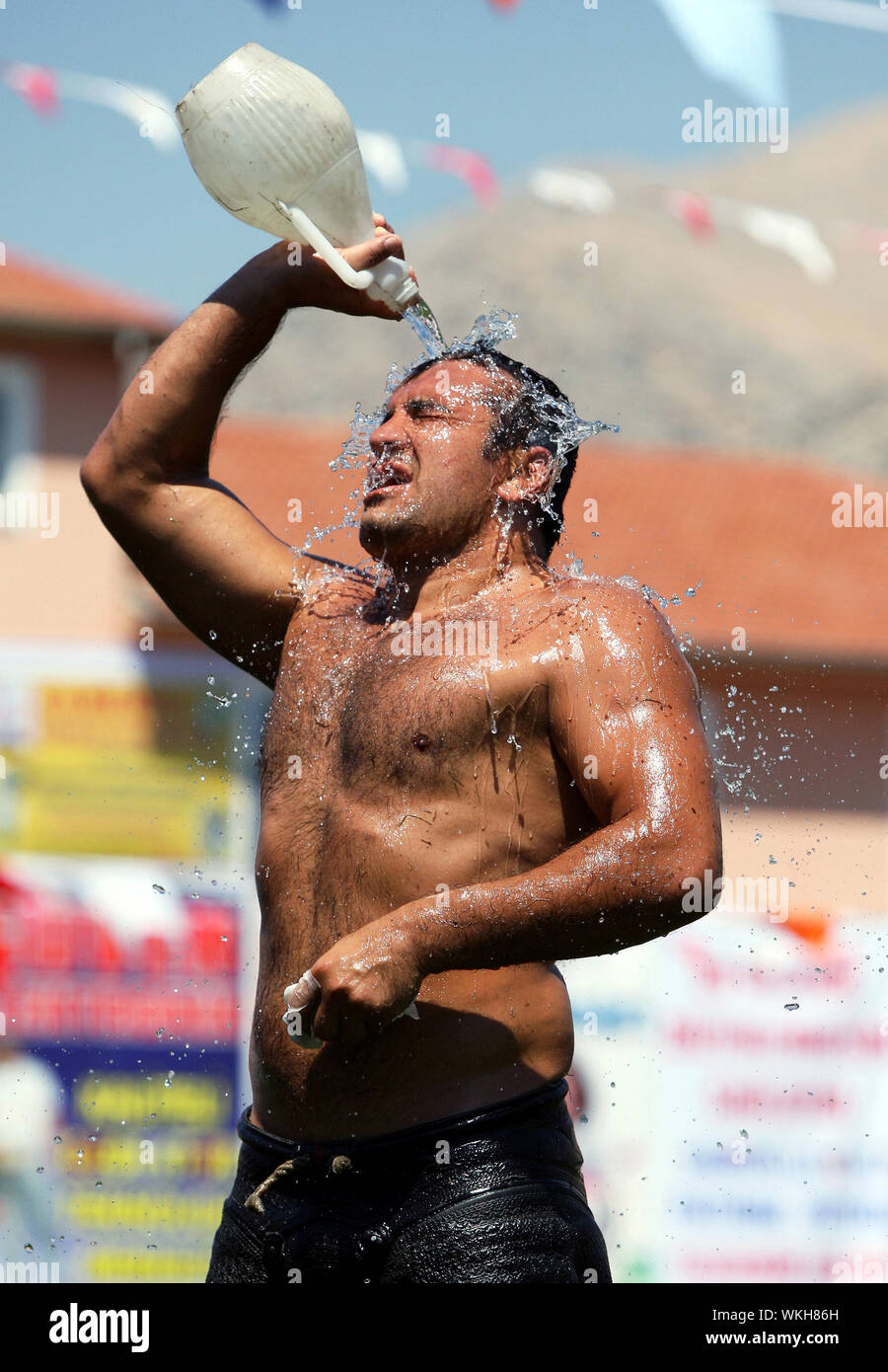 A heavyweight wrestler cools down by pouring water over his body after ...