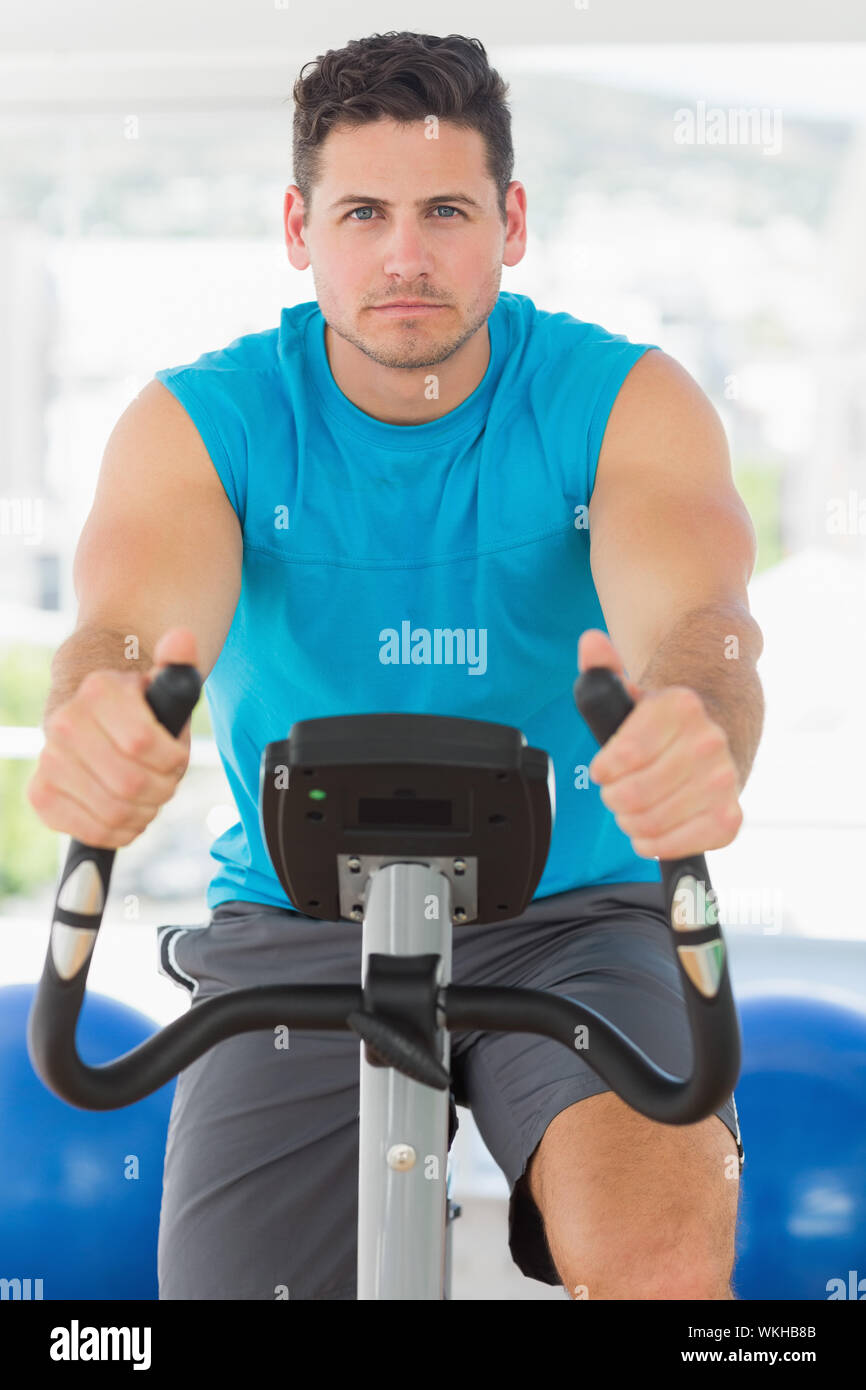 Portrait of a serious young man working out at spinning class in gym ...