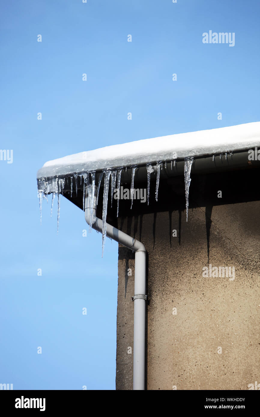 small icicles hanging from the eaves of a house against a blue sky with ...