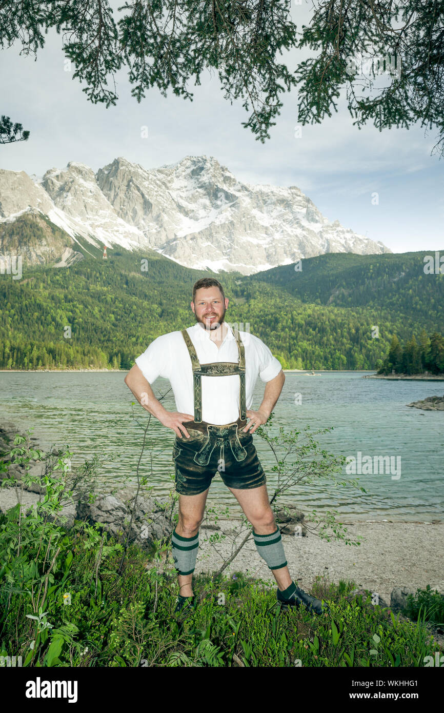 A traditional bavarian man at lake Eibsee with the Zugspitze mountain ...