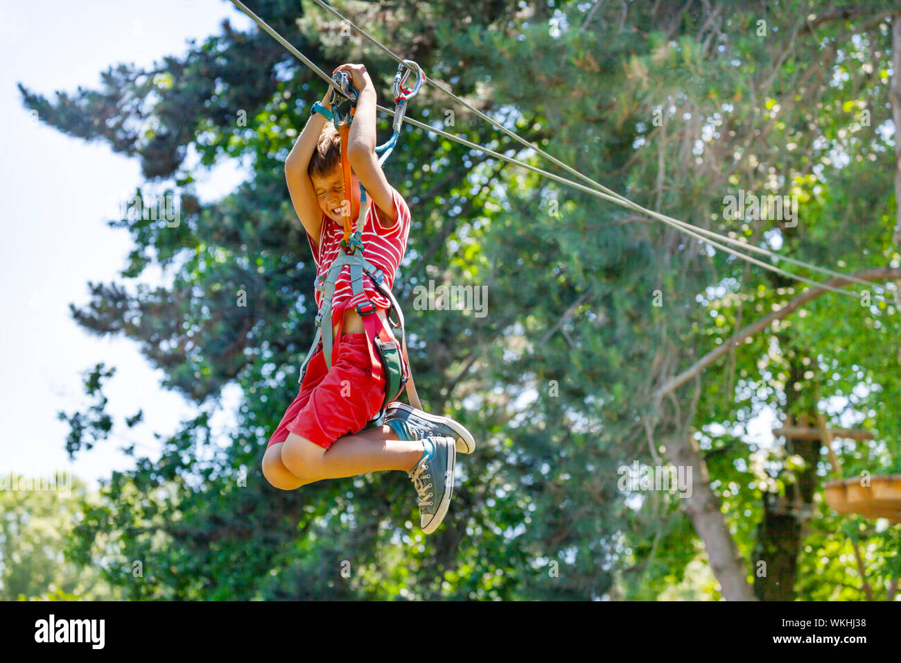 Boy scream and fast slide zip line with trolley Stock Photo - Alamy