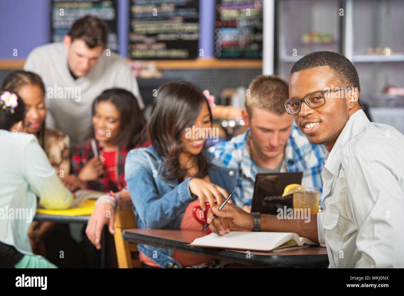 Cute man doing homework with friends in cafe Stock Photo - Alamy