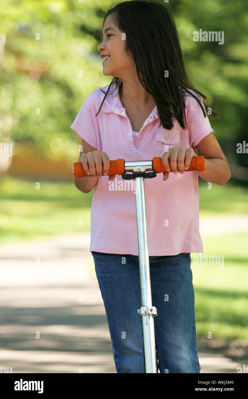 Girl riding a scooter on sidewalk Stock Photo - Alamy