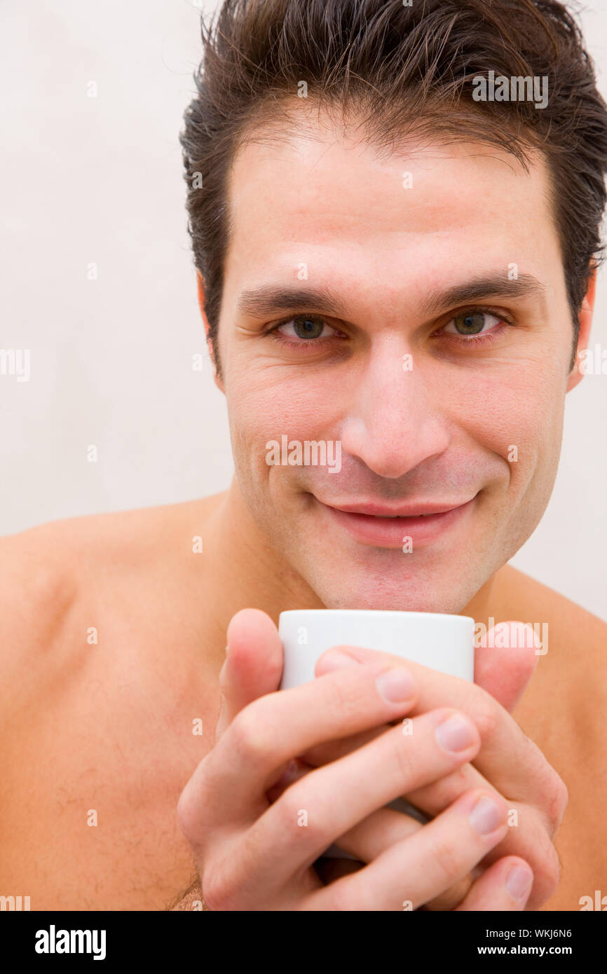 Smiling young man holding cup Stock Photo - Alamy