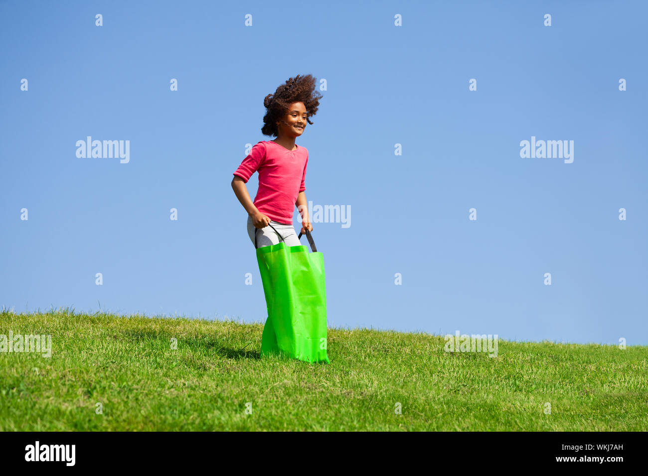 Little girl play sack race game jumping hoping Stock Photo - Alamy