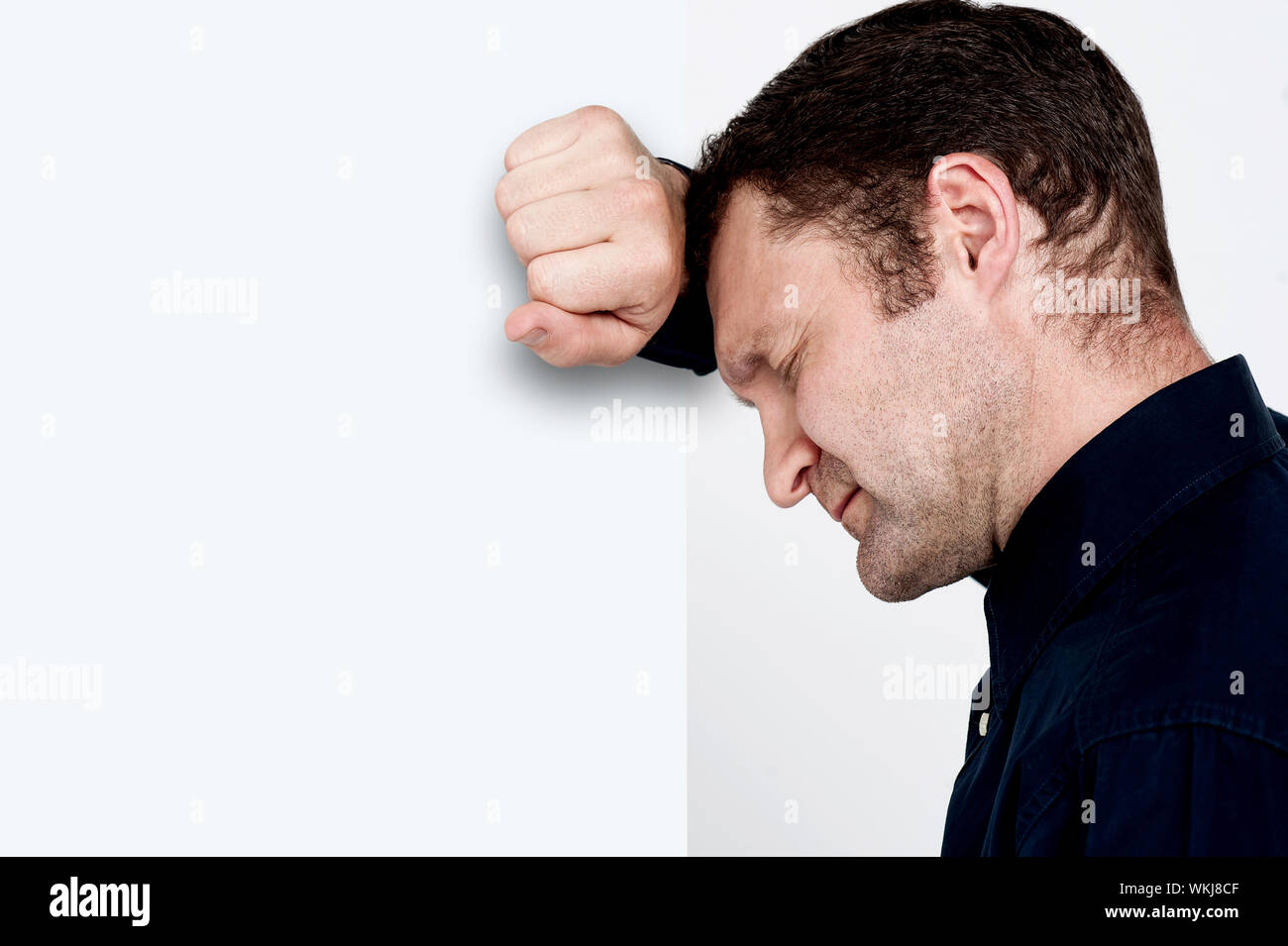 Side view of depressed man leaning his head against a wall Stock Photo ...