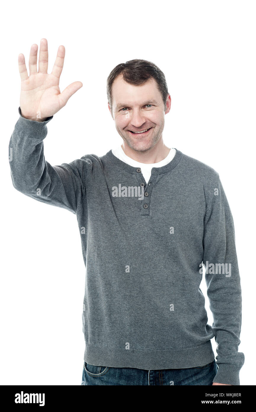 Smiling man standing and waving his hand Stock Photo - Alamy