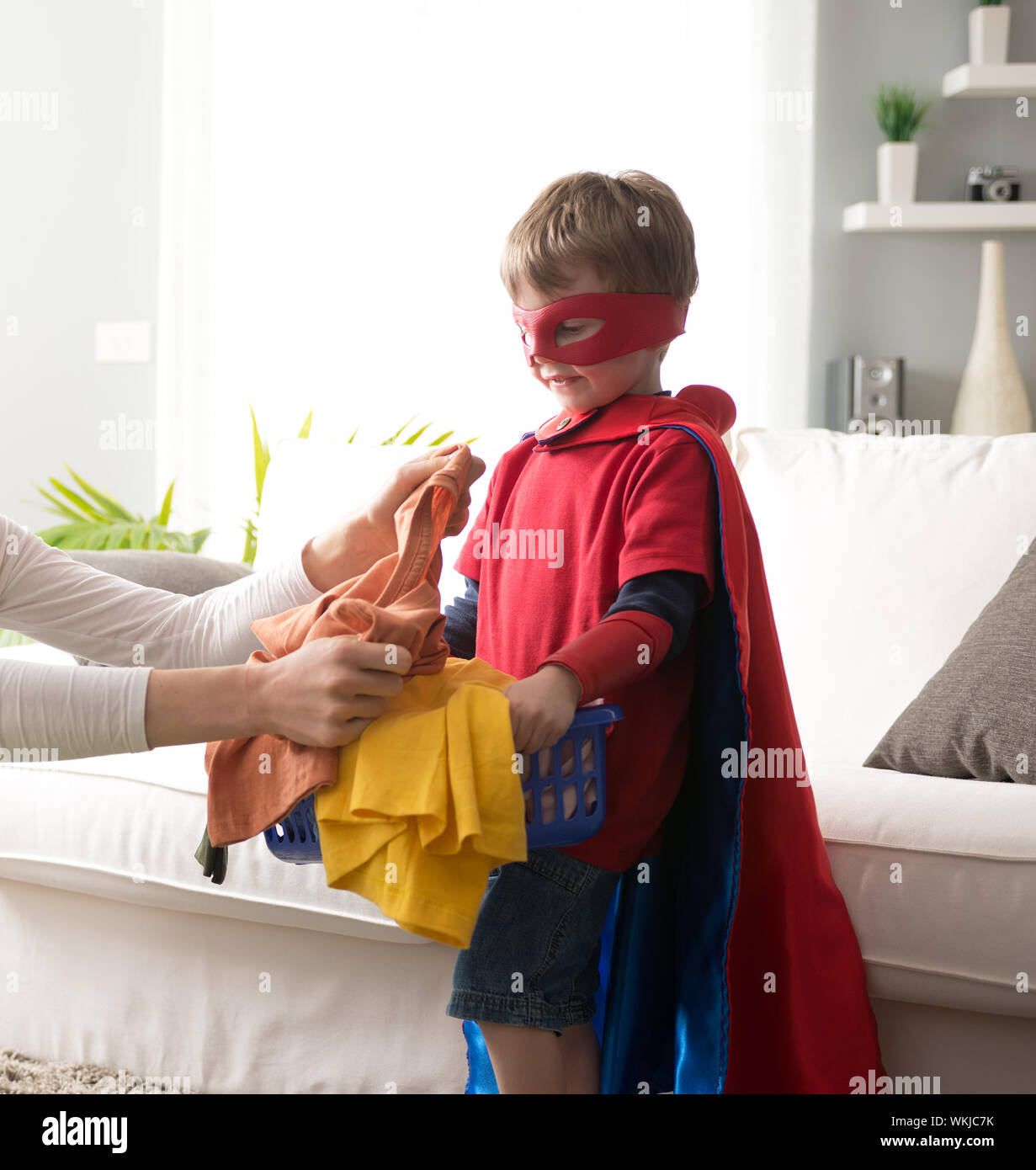 Little superhero boy helping out with laundry and carrying a load of ...