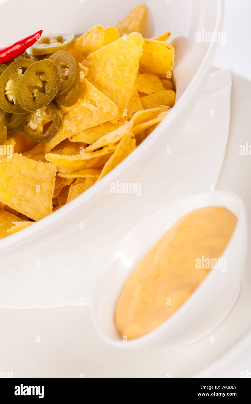 Bowl of crisp golden corn nachos with cheese sauce or dip and olives ...