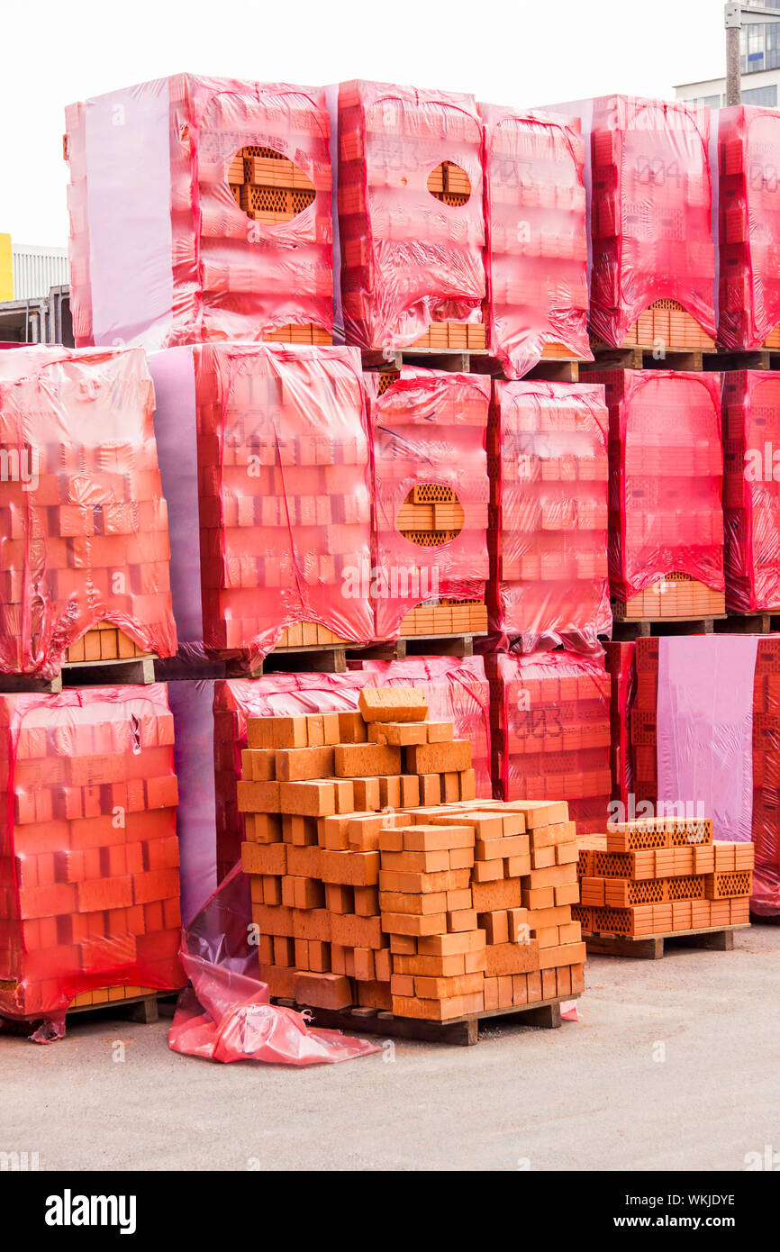 Red clay building bricks stacked on pallets still wrapped in their ...