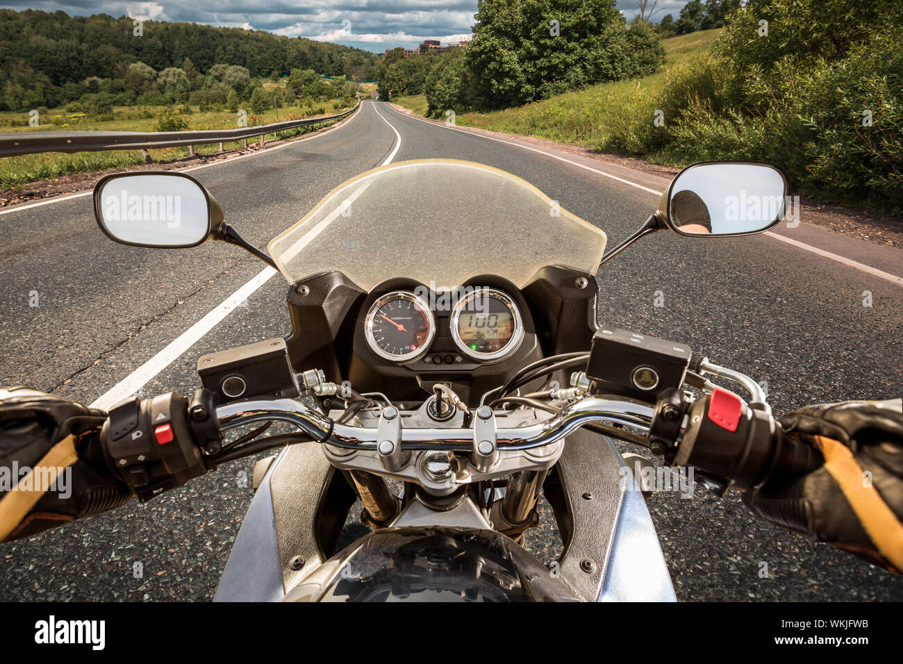 Biker driving a motorcycle rides along the asphalt road. First-person ...