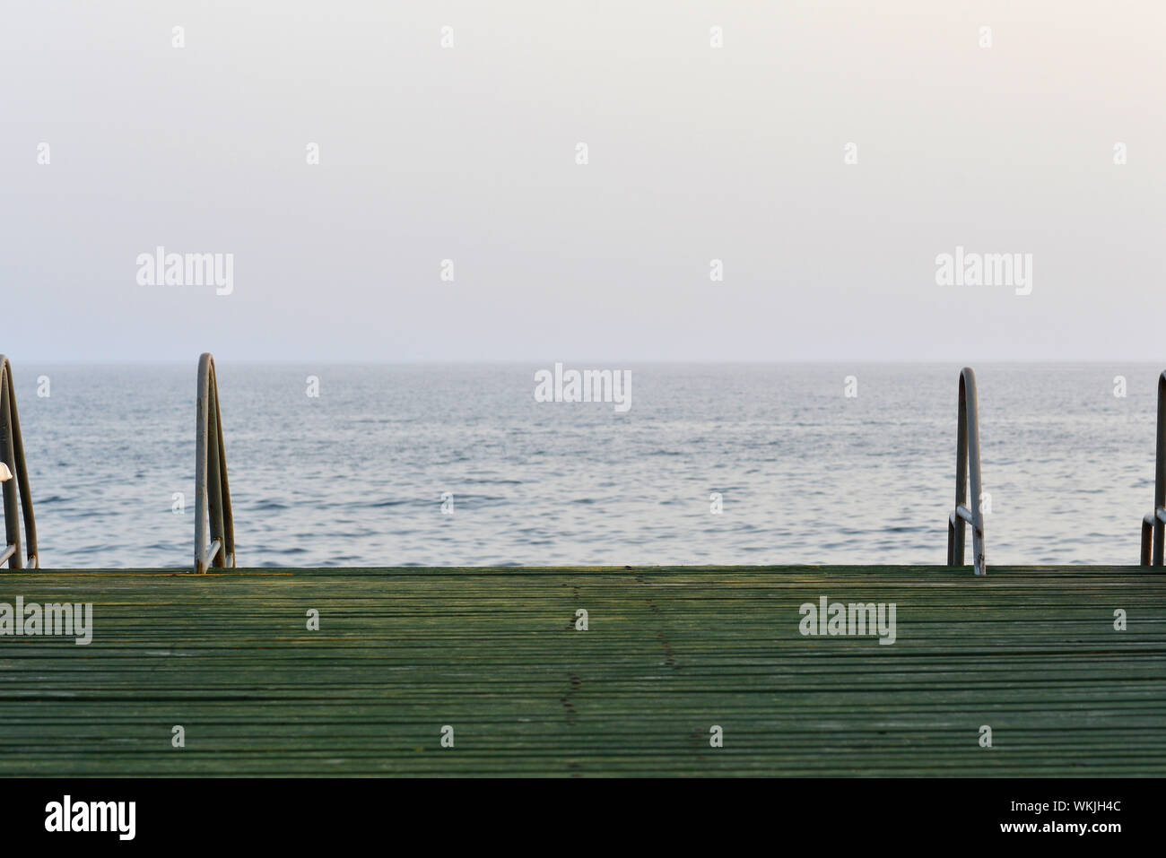 Wooden pier with metal handrails on the background of sea and sky Stock ...
