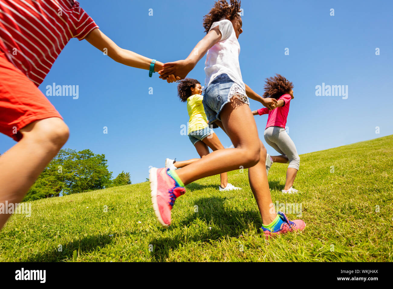 Kids in profile run and pull hands of each other Stock Photo - Alamy