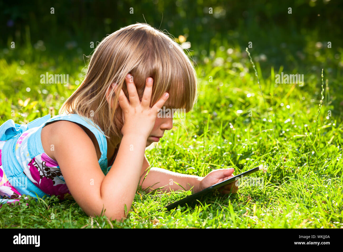 Little girl usng a touch pad in a summer garden Stock Photo - Alamy