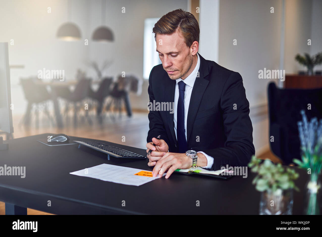 Businessman going over paperwork while sitting alone at his desk and in ...