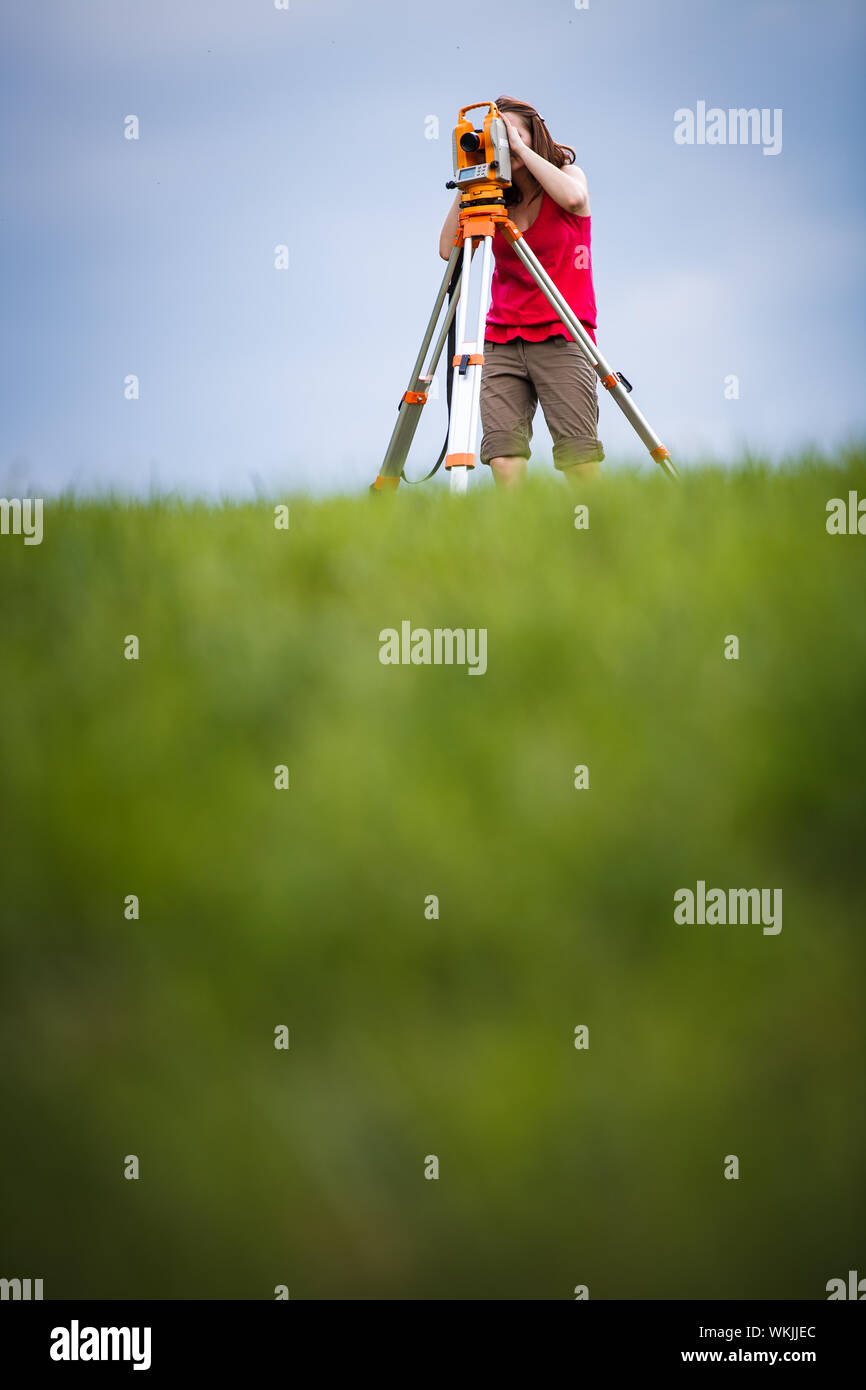Young, female land surveyor at work - using the theodolite level ...
