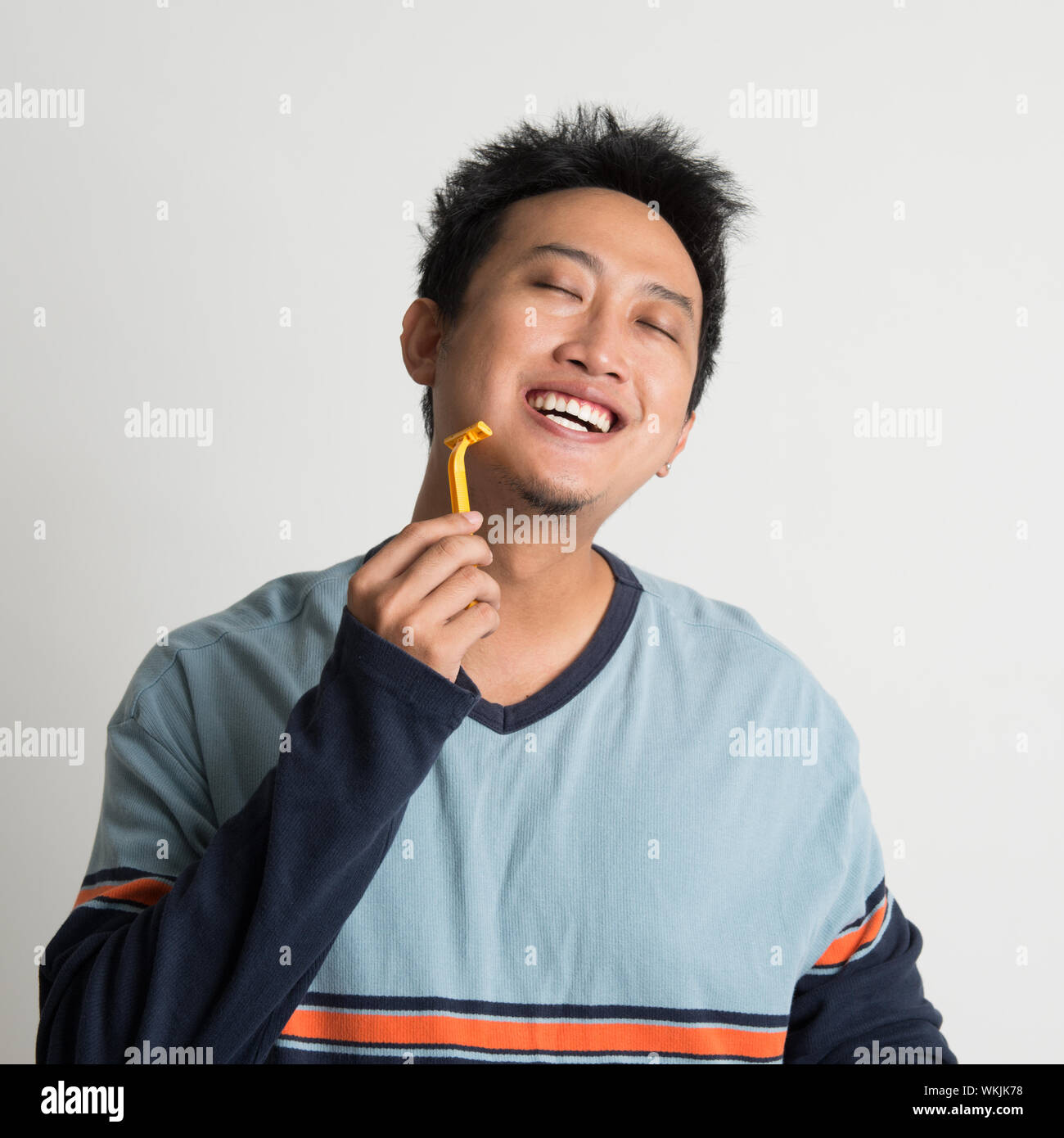 Asian male shaving his beard in a morning, on plain background Stock ...