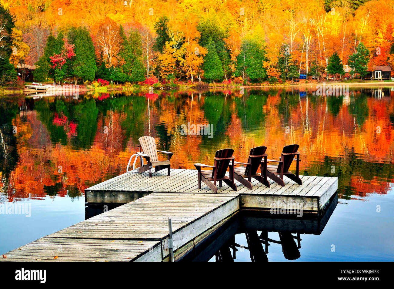 Wooden dock with chairs on calm fall lake Stock Photo - Alamy