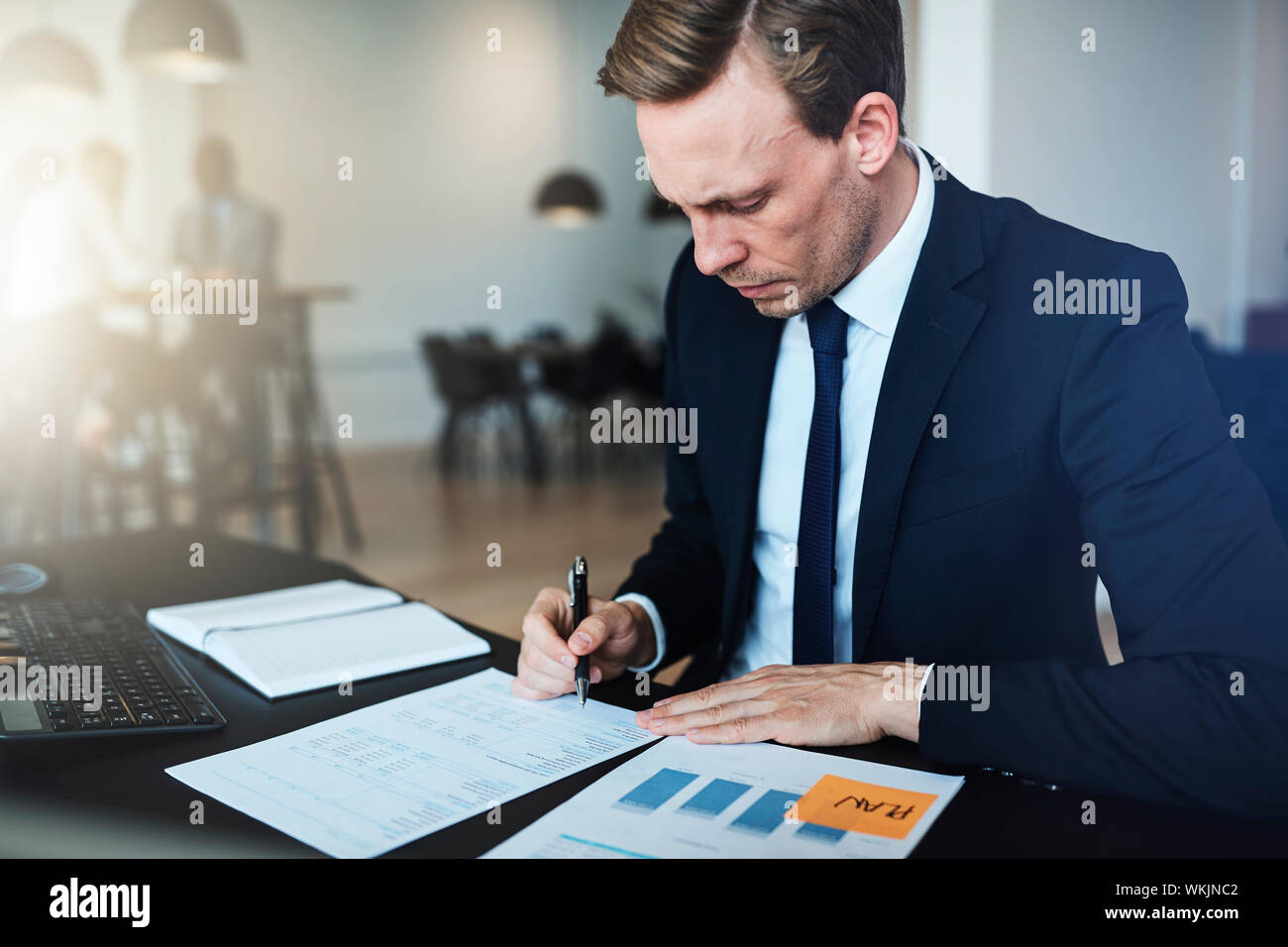 Businessman signing papers and going over documents while sitting at ...