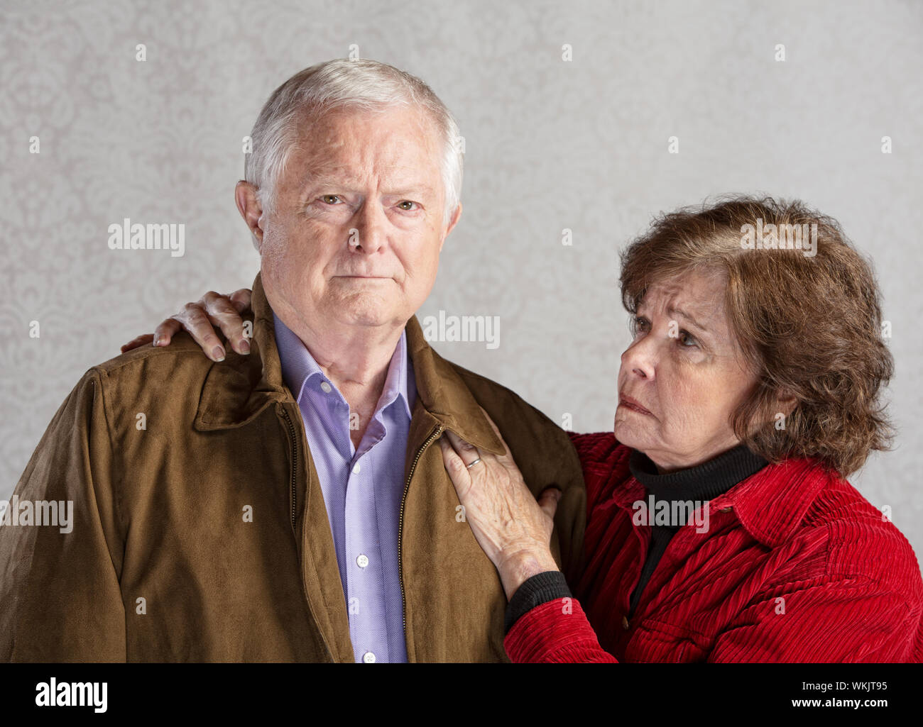 Concerned senior husband and wife over gray background Stock Photo - Alamy
