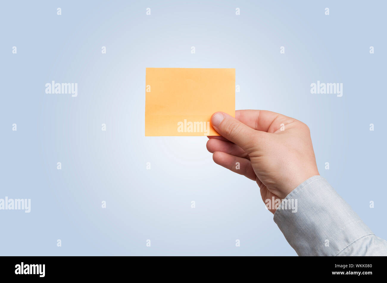 Man hand in light blue shirt hold an orange blank sticky note on ...