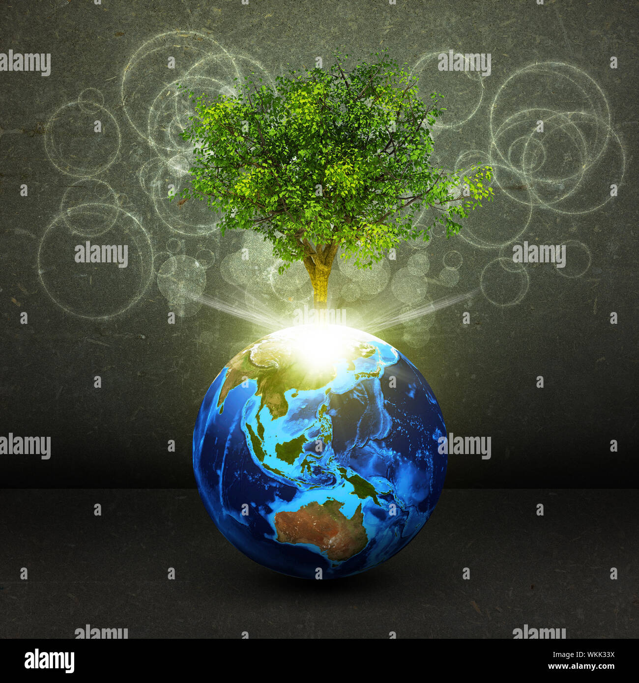 Earth with magical green tree and rays of light on dark background ...