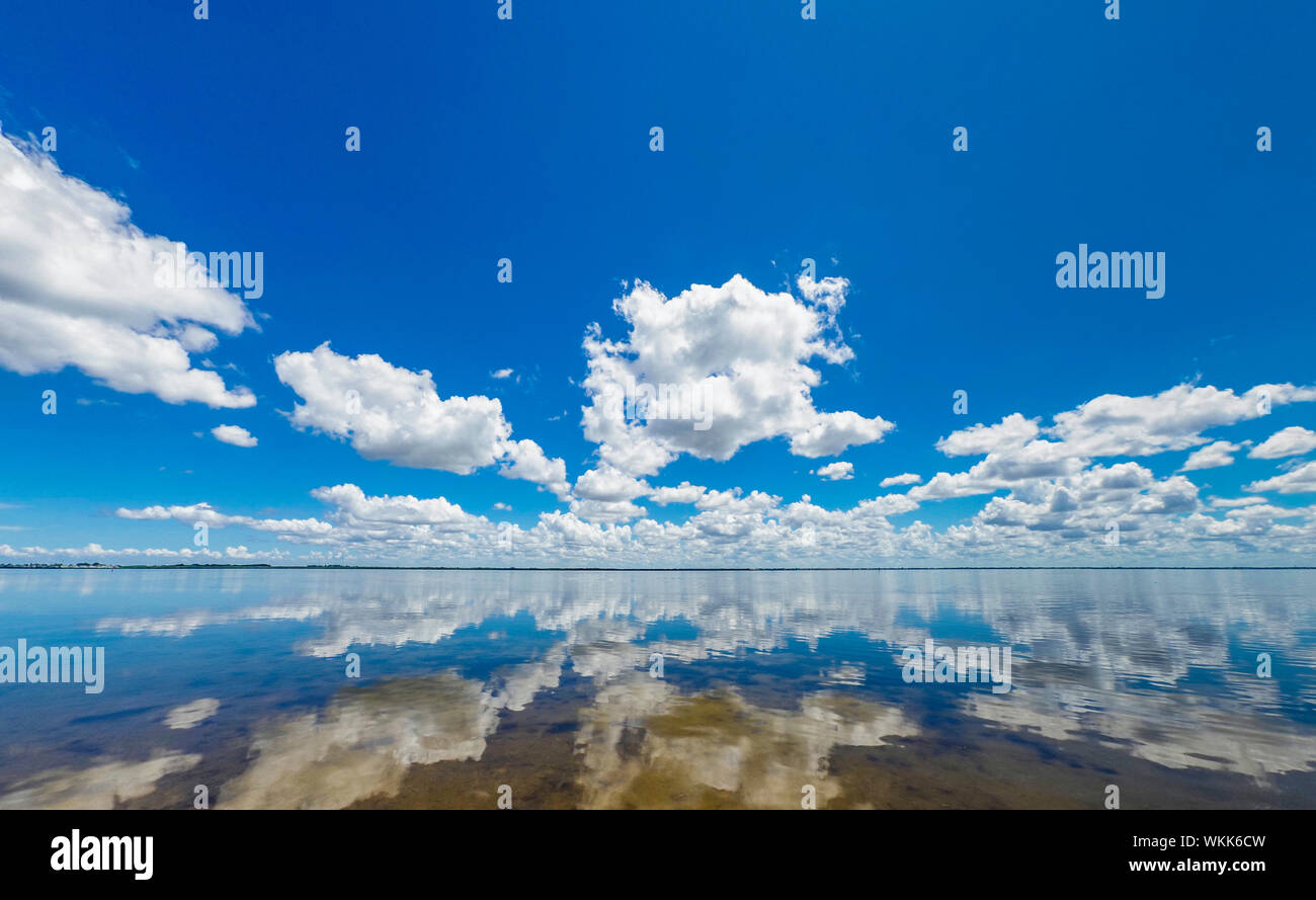 White clouds in blue sky reflecting in Sarasota Bay taken from Longboat ...