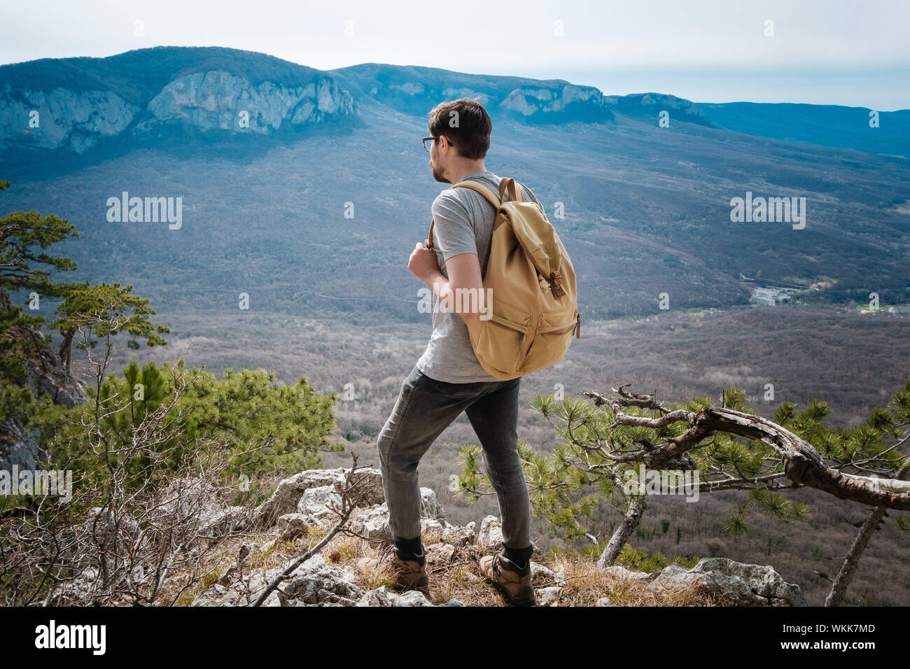 young hipster man in the spring mountains. Hipster with a backpack ...