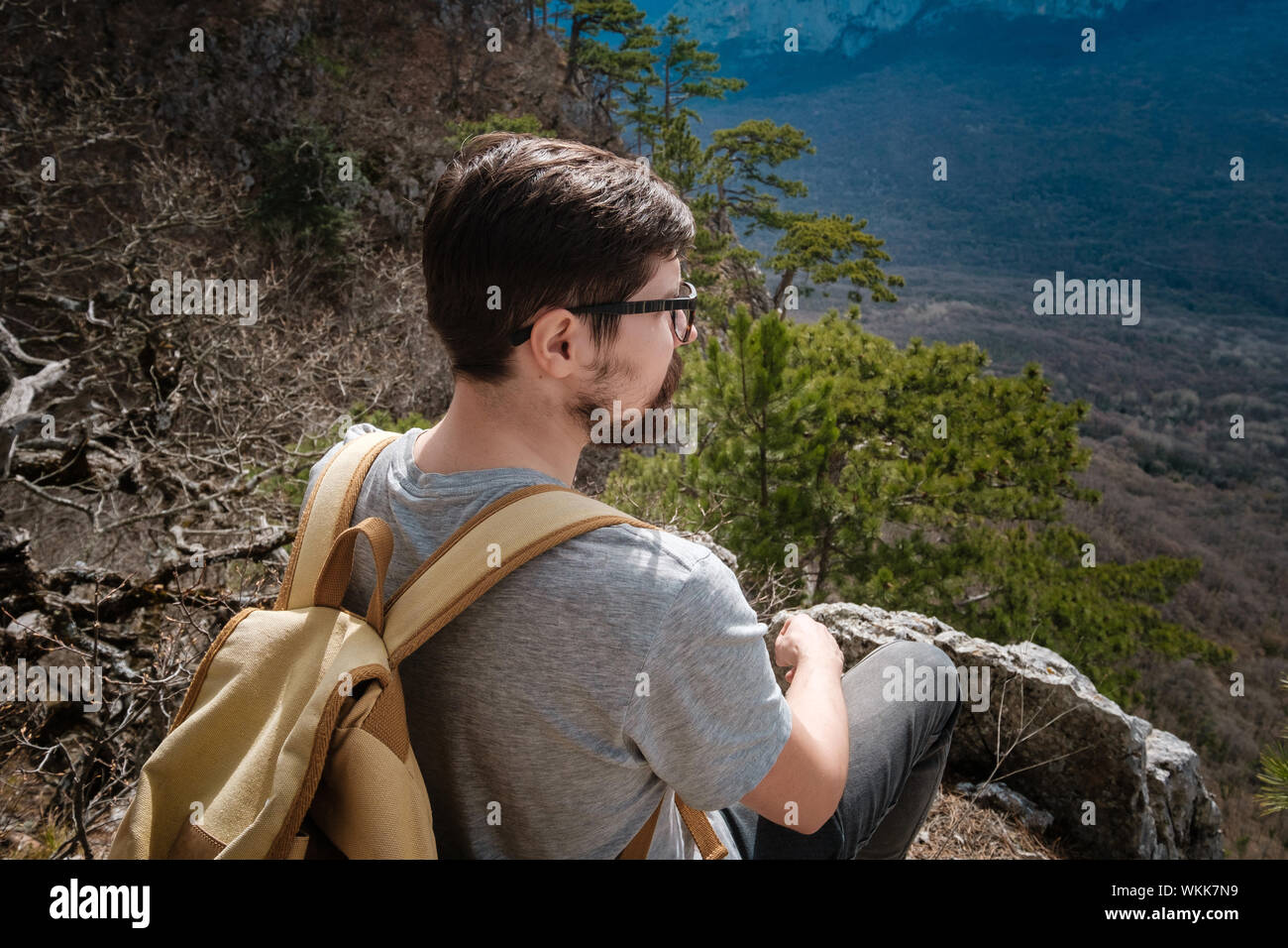 young hipster man in the spring mountains. Hipster with a backpack ...