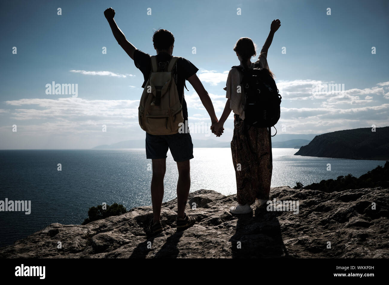 Hikers with backpack standing on top of a mountain with raised hands ...